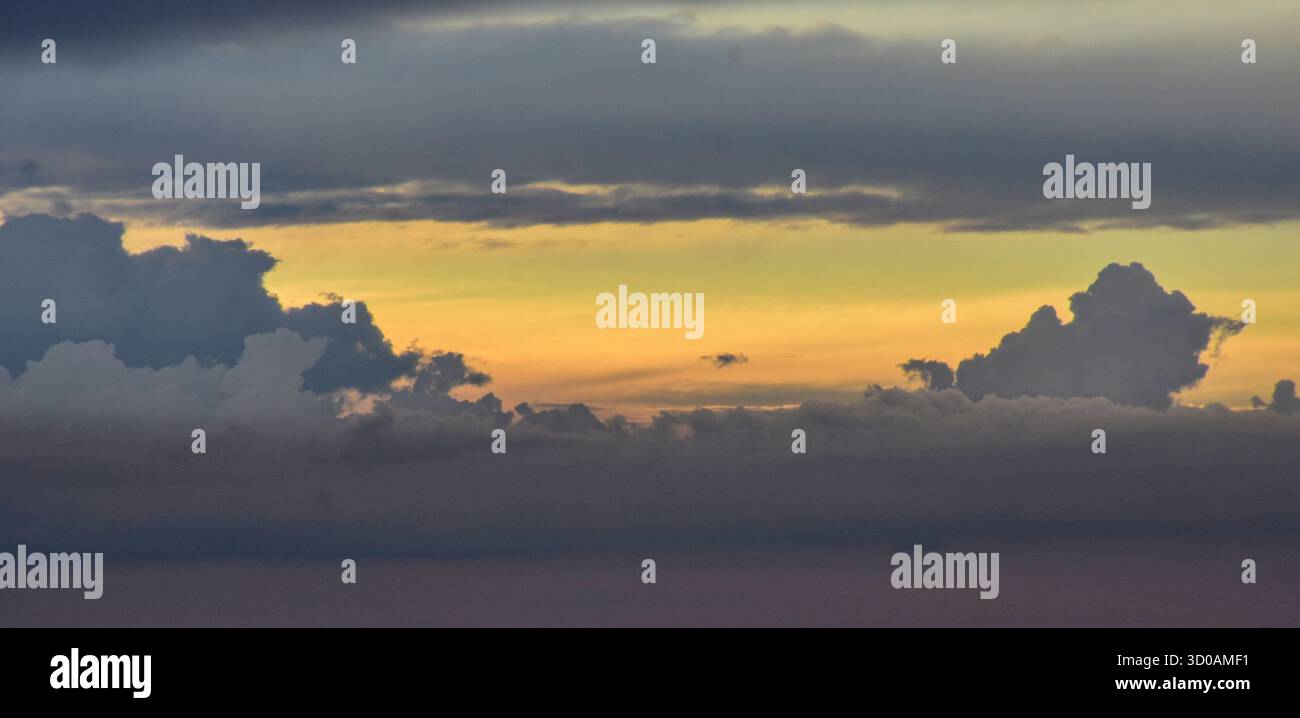 Soft pastel sunset clouds illuminated by warm golden light create a ...