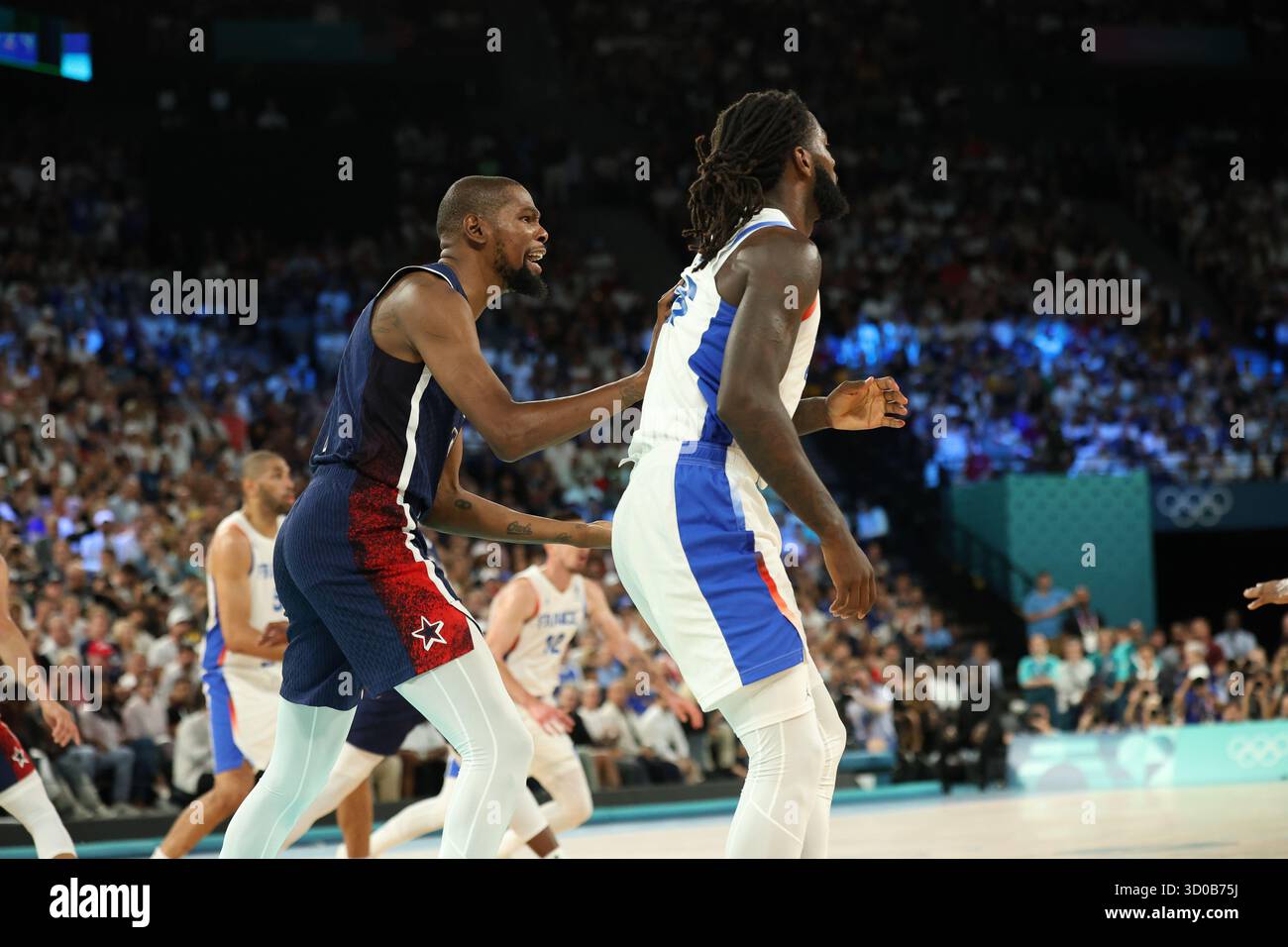 August 10th, 2024 - Paris, France: Mathias Lessort of France is guarded ...