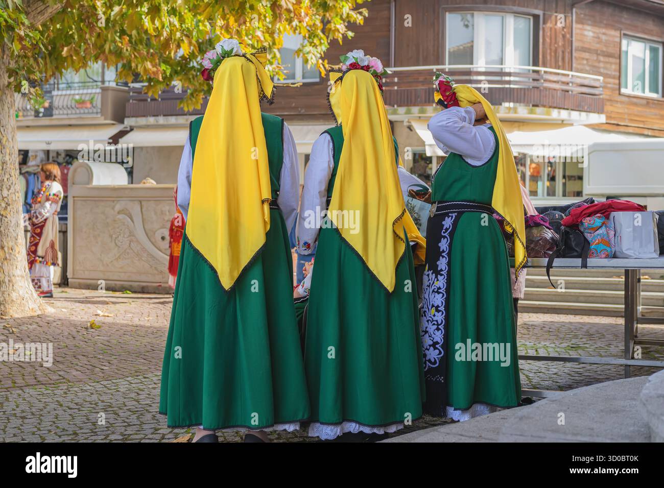 Three women in traditional green and yellow Bulgarian folk costumes ...