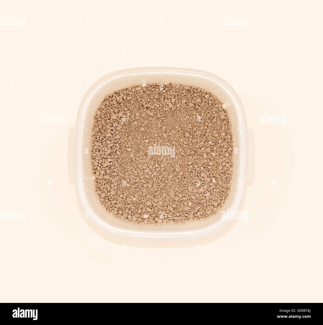 Brown cat litter granules in a transparent container against a soft ...
