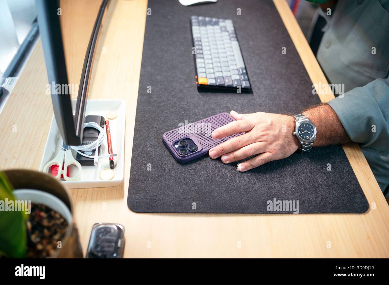 Hand resting on smartphone beside keyboard Stock Photo - Alamy