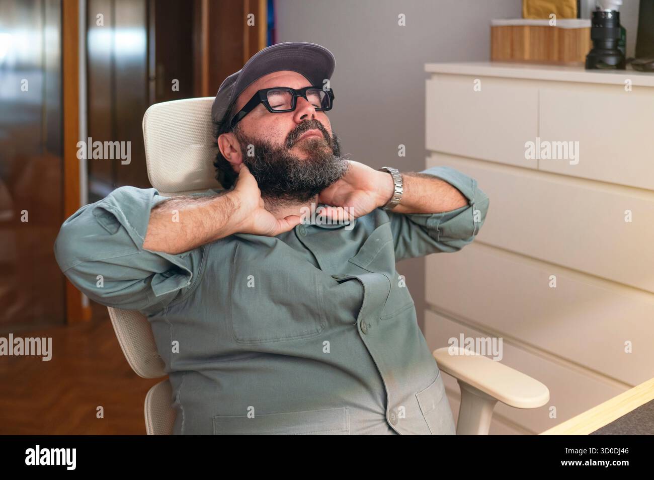 Man leaning back in chair massaging his neck Stock Photo - Alamy