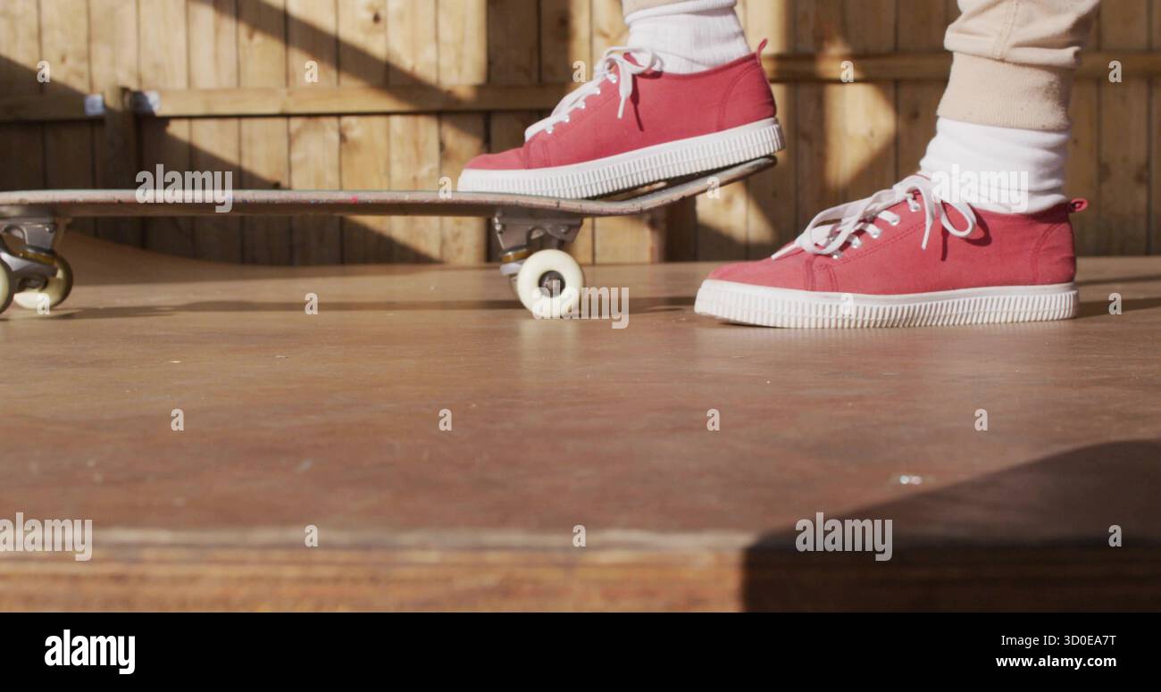 Balancing skateboarder's legs and feet on skateboard deck on backyard ...