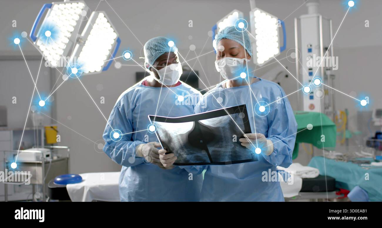 Two surgeons wearing scrubs reviewing chest X-ray film in operating ...