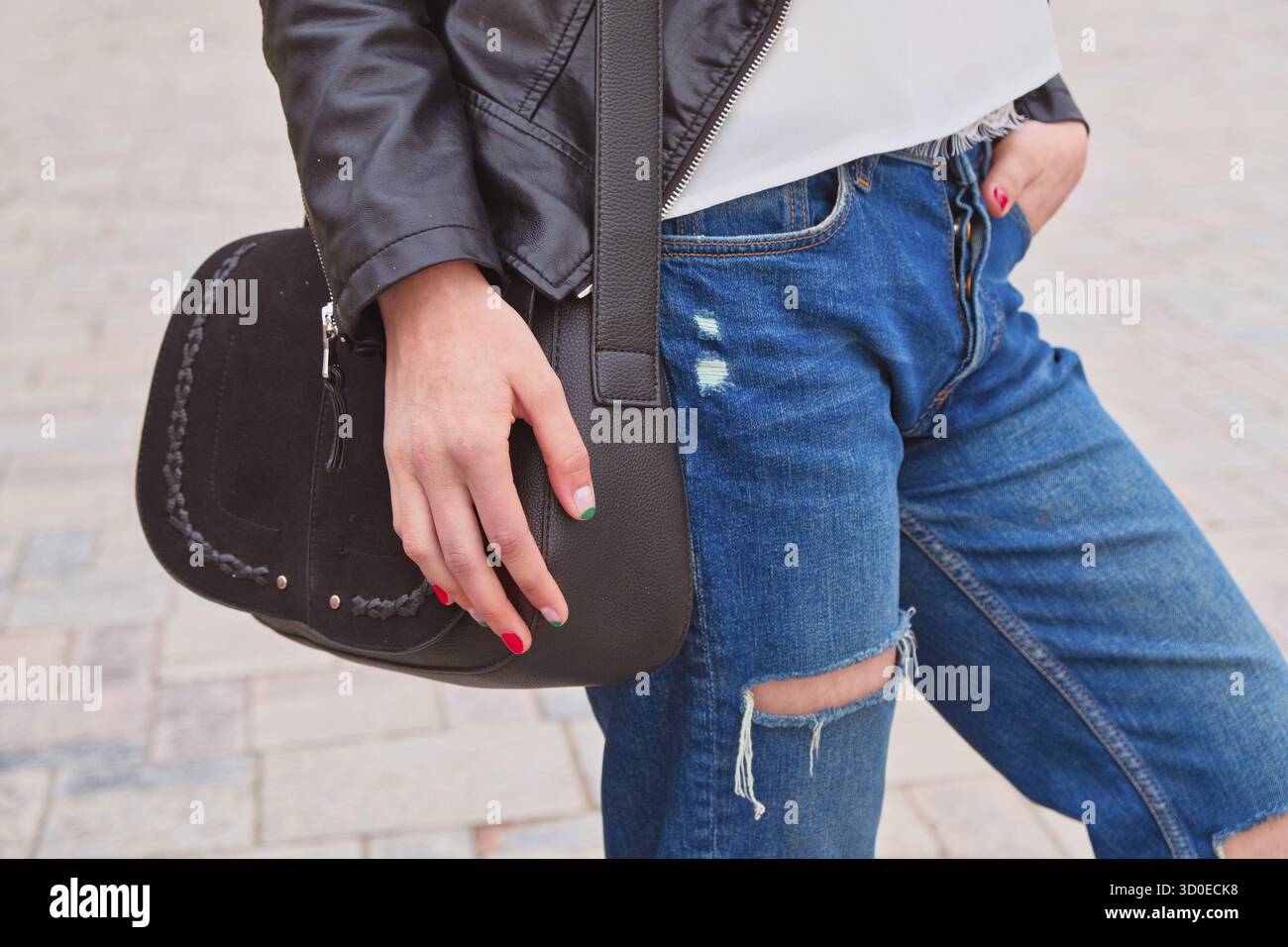 Side view of Girl in ripped jeans with black leaser handbag hanging on ...
