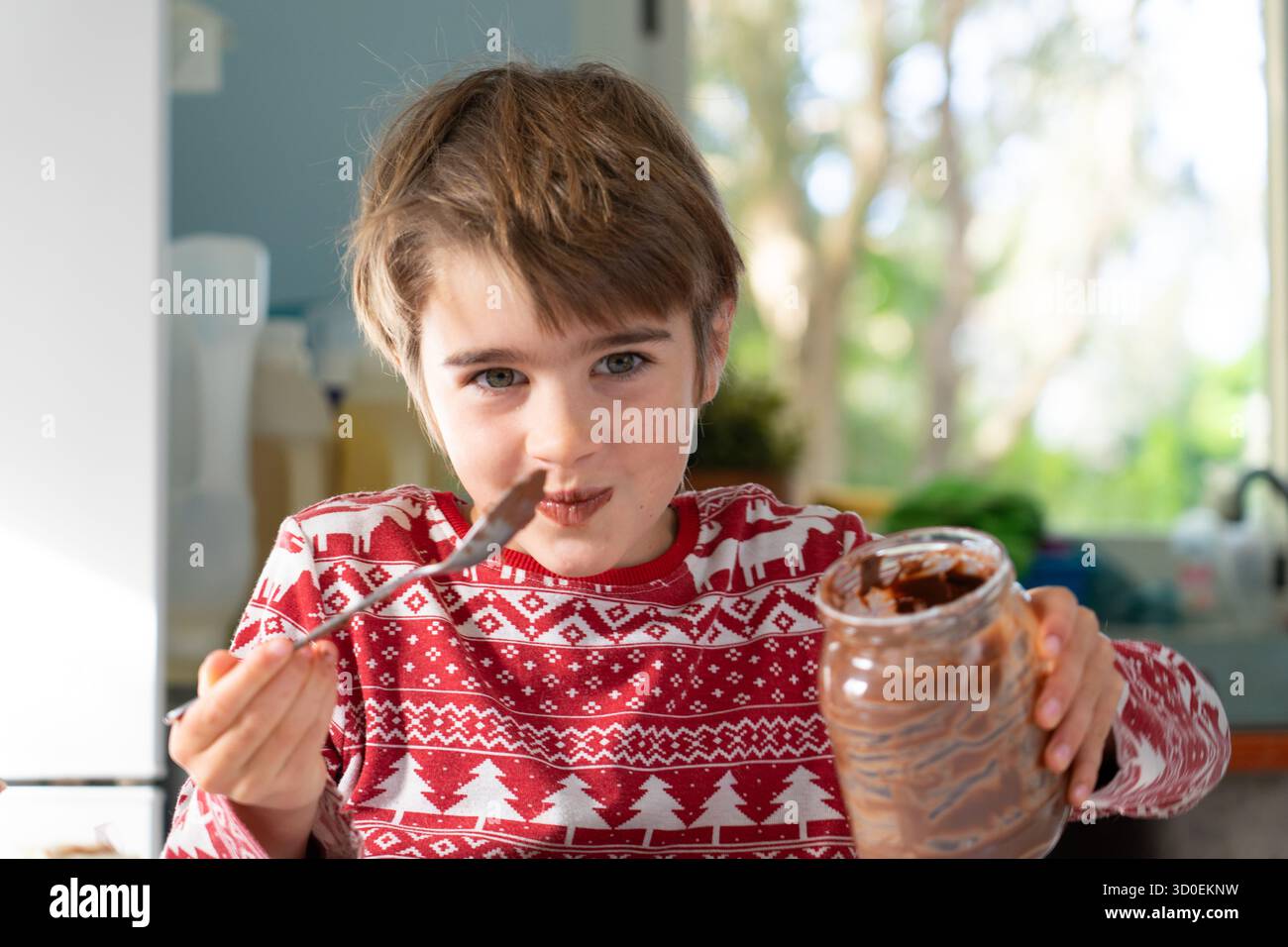 Child wearing a christmas sweater enjoying a messy chocolate snack in ...