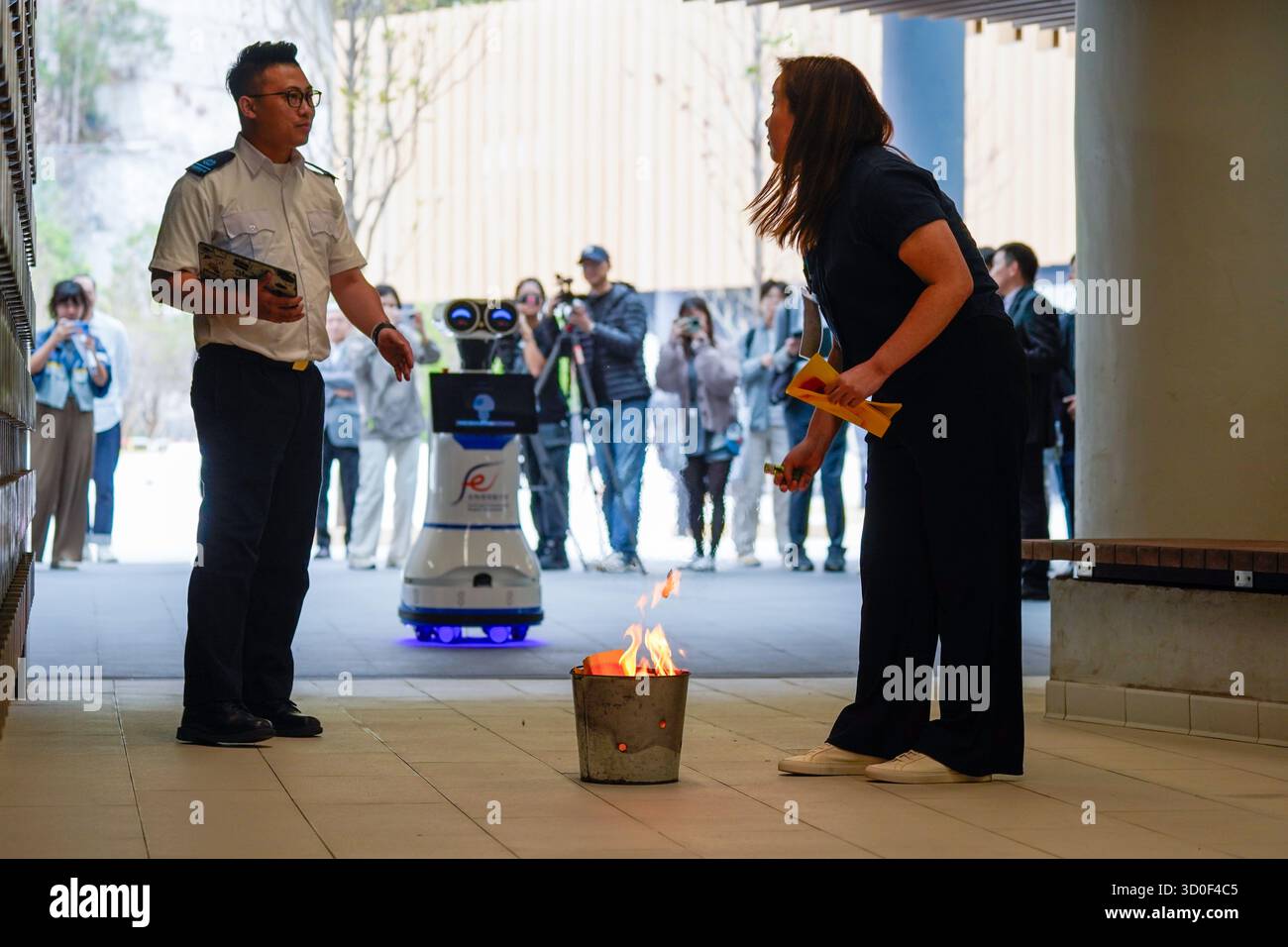 A security guard stopping a woman from burning paper offerings during a ...