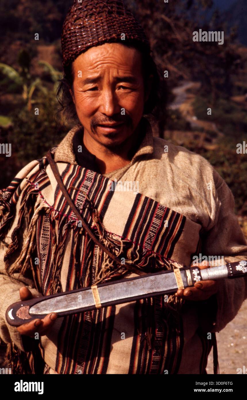 Lepcha man in traditional bamboo hat and woven clothing holding knife ...