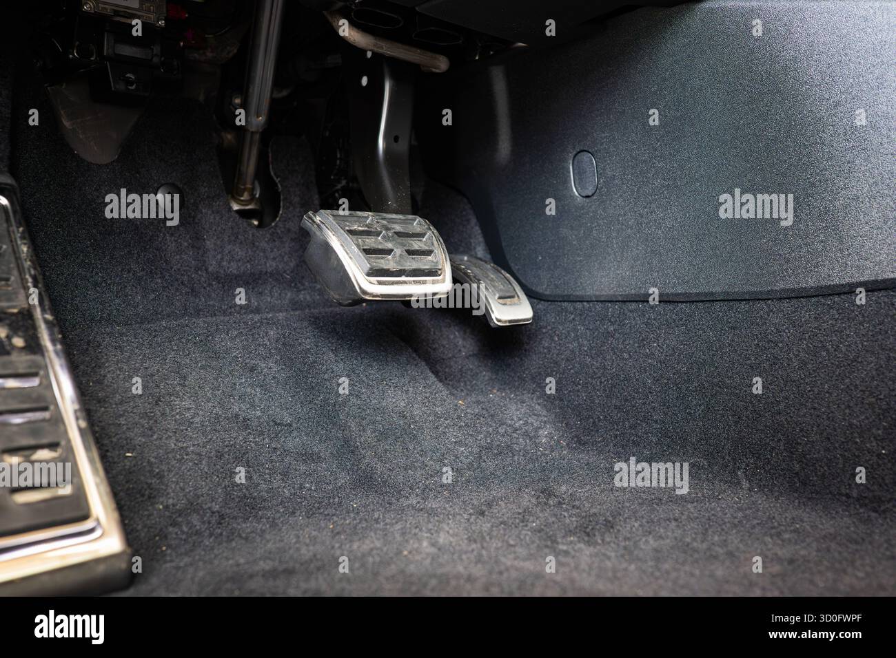 New car gas and break pedals inside driver footwell. Wide angle, close ...