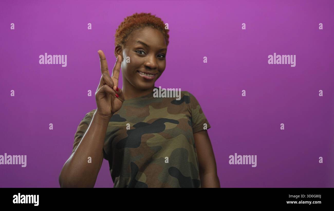 Woman soldier in camouflage uniform smiles holding fingers in money ...