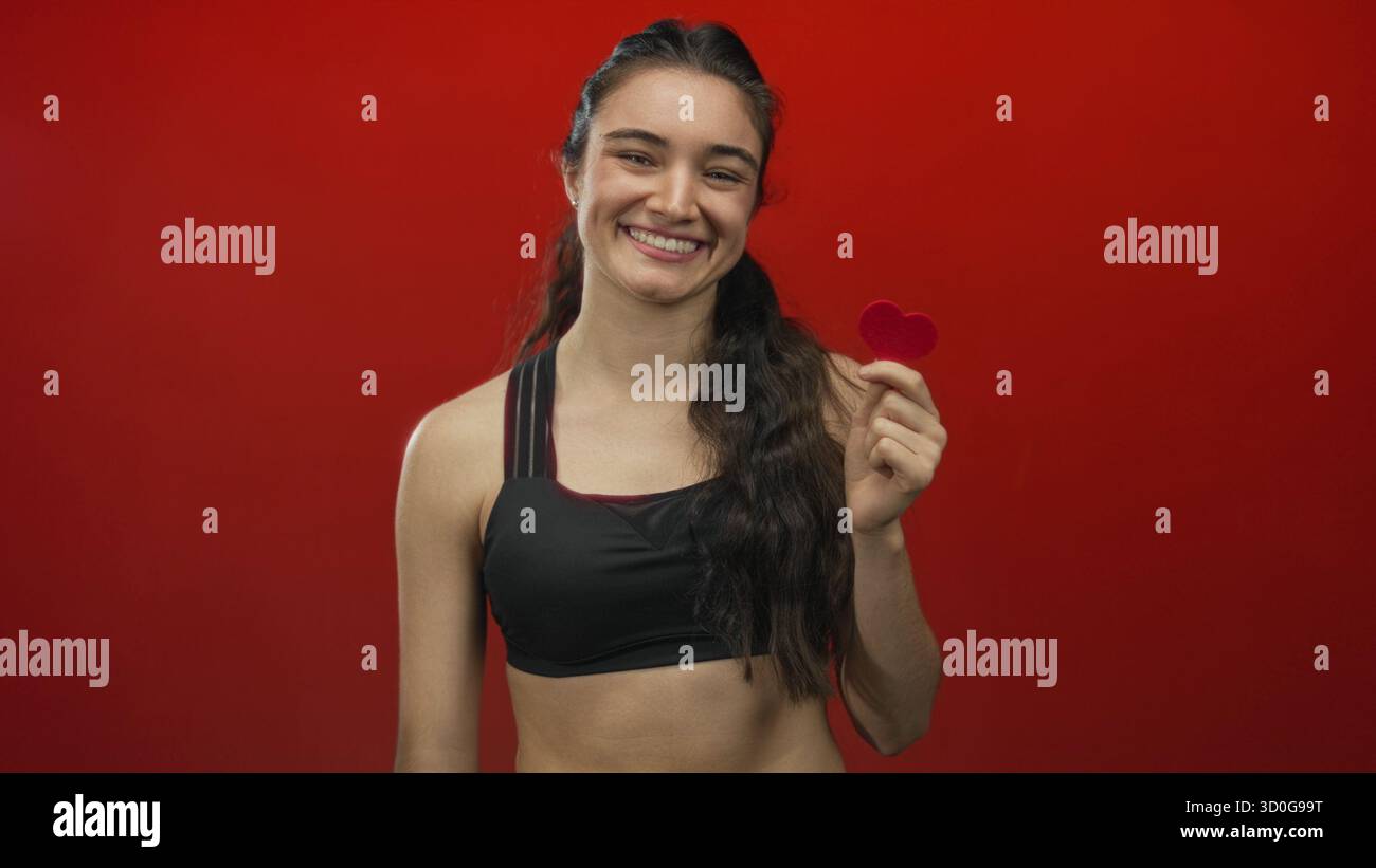 Woman holds red felt heart close to her smiling face in a studio ...