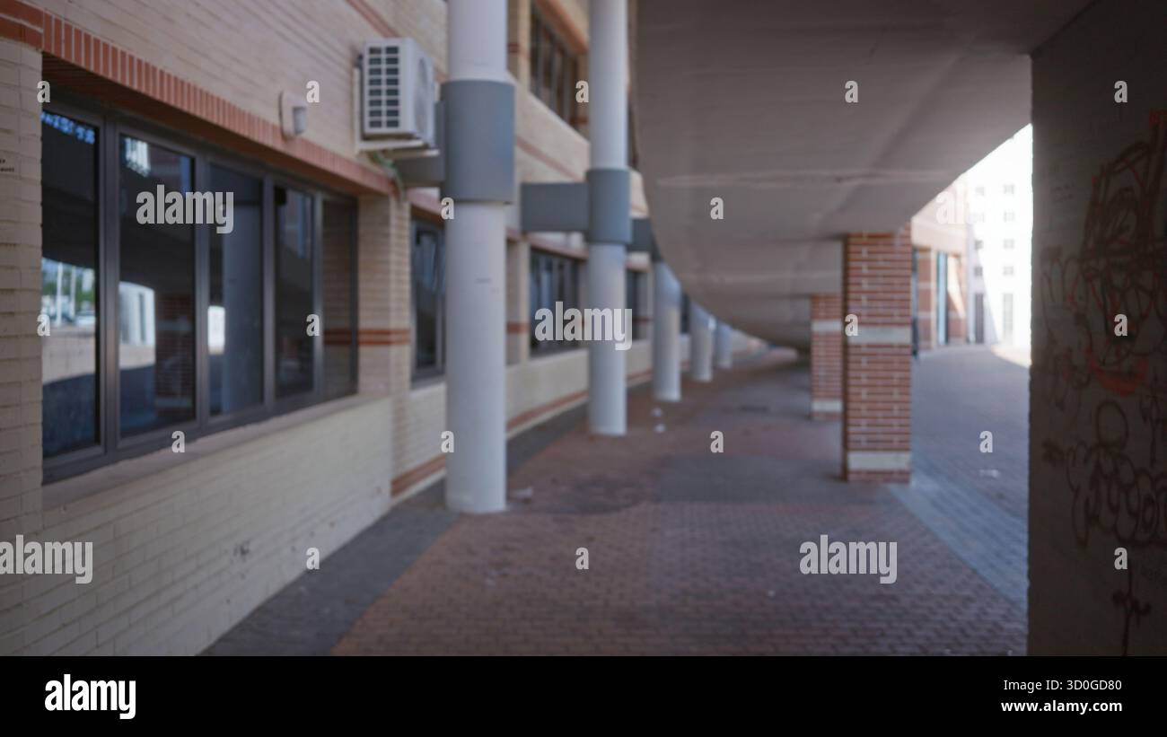 Covered brick arcade with columns, windows and curved overhang in soft ...