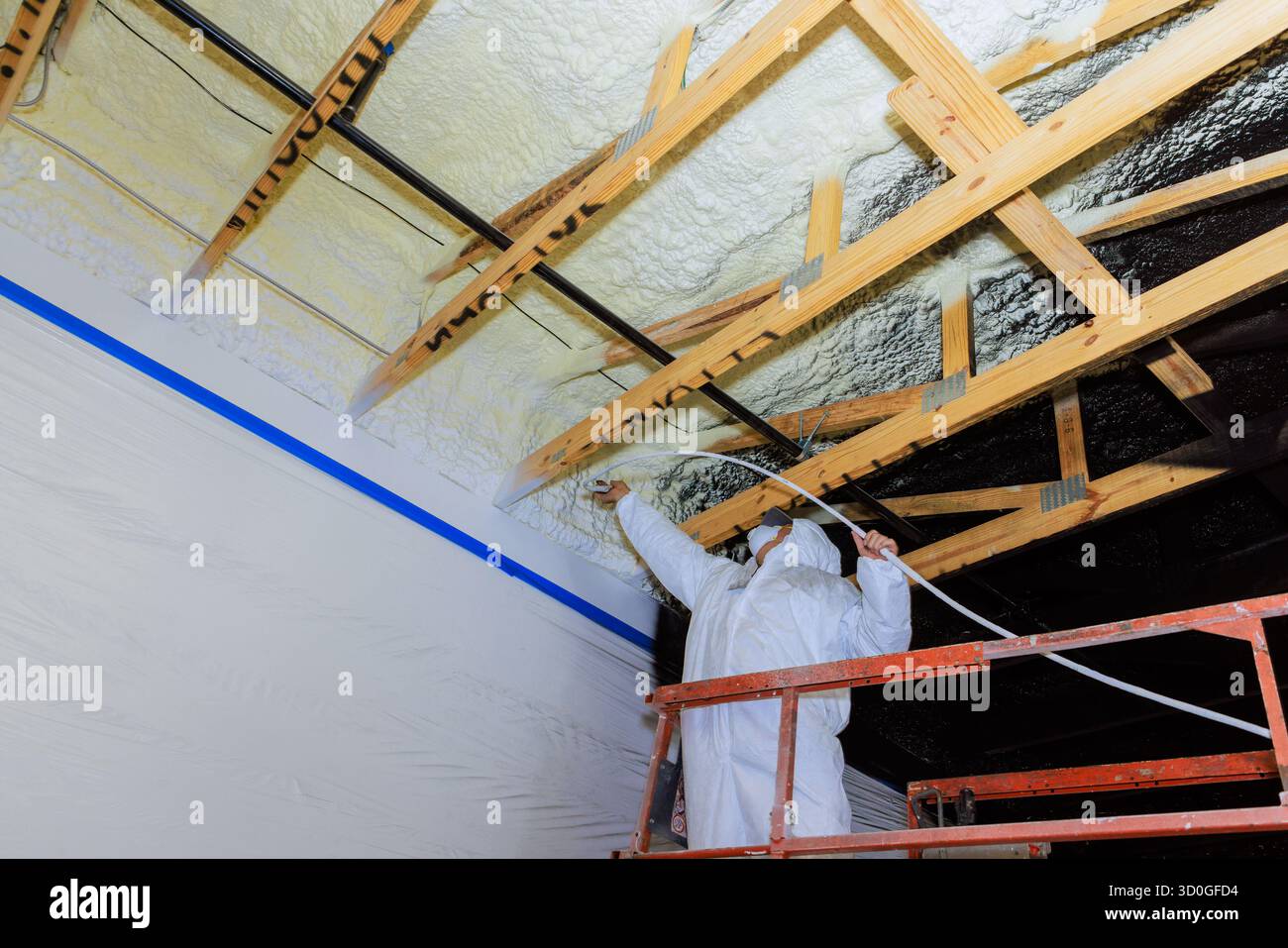 Painter in protective gear uses spray machine to apply refractory paint ...