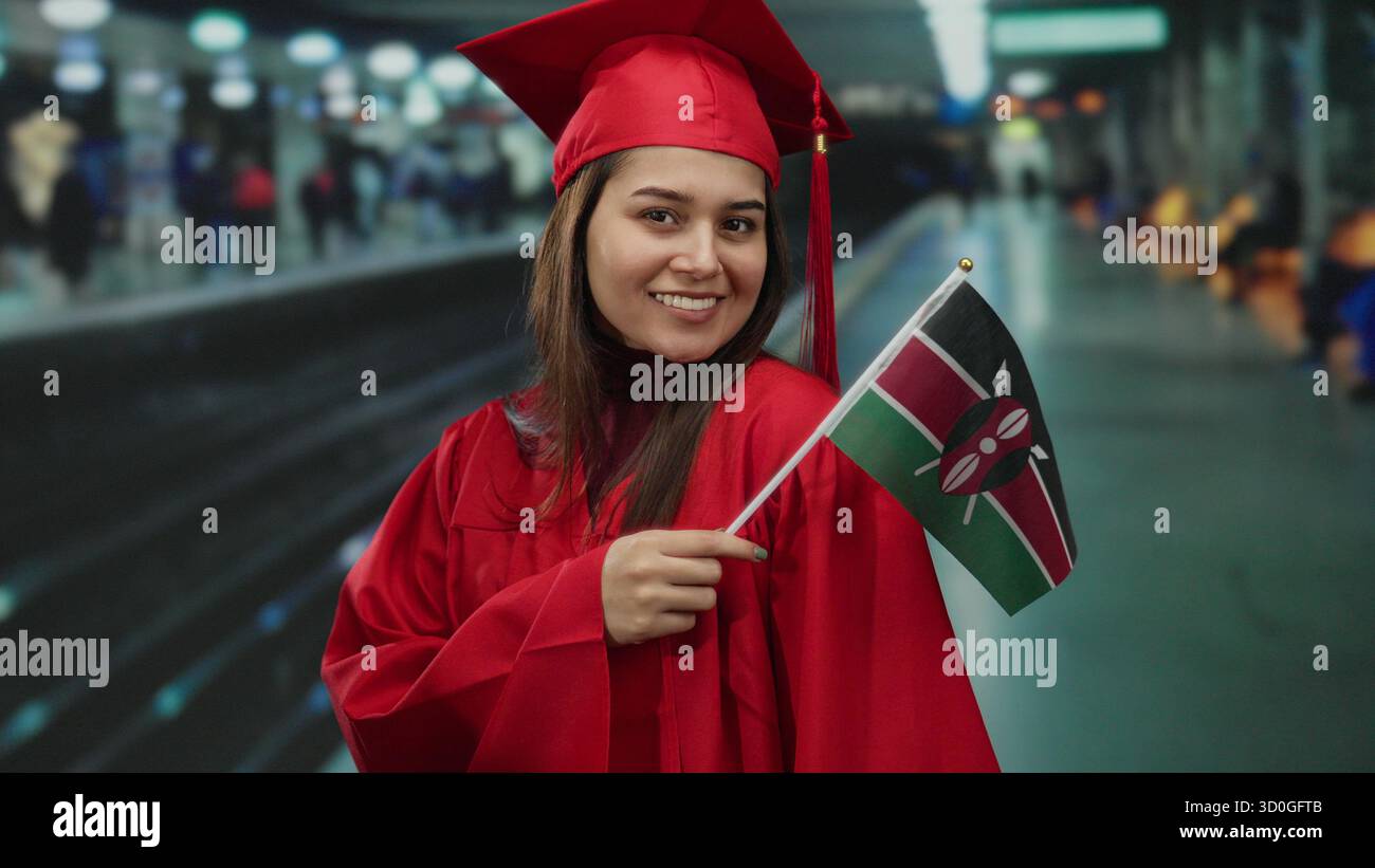 Young woman in red graduation gown holding kenyan flag at indoor train ...