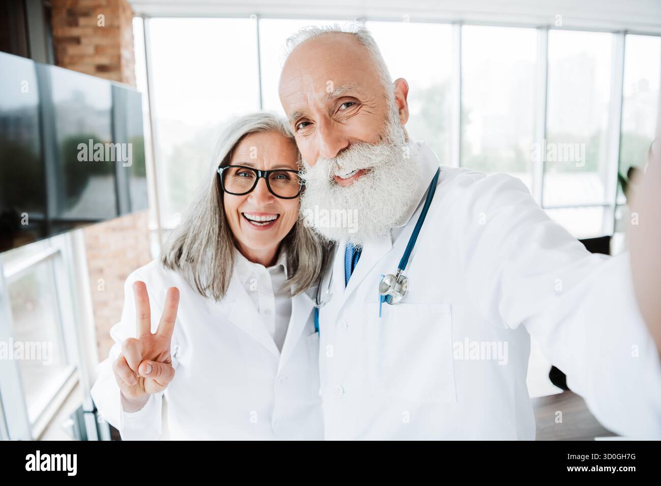 Funny doctor duo selfie in bright clinic with senior couple of ...