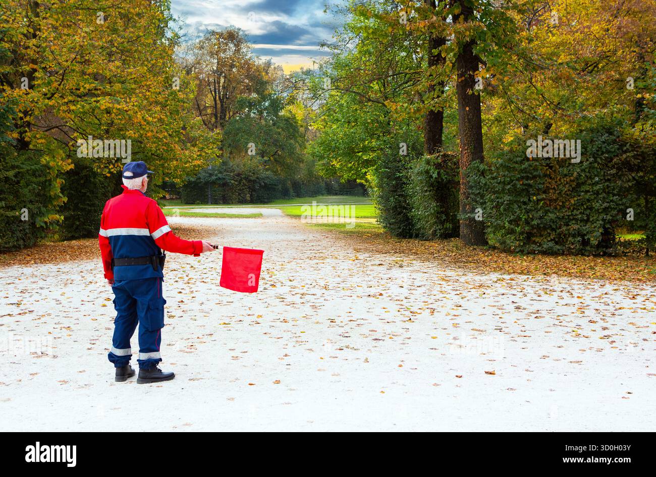 Race marshal stands on park trail holding red flag ensuring safety ...
