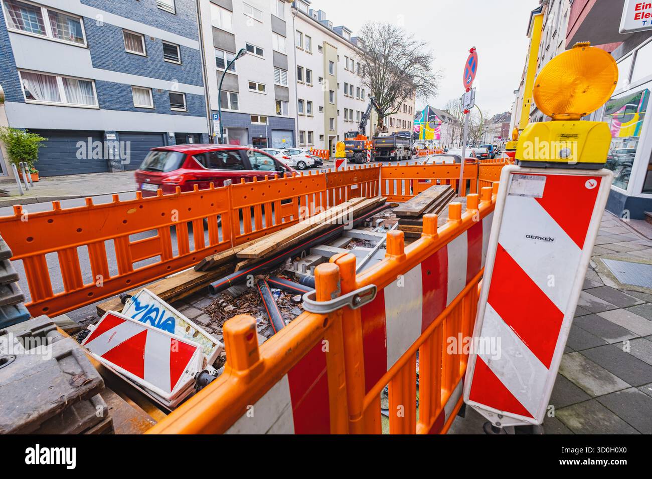 A construction site on a city street, enclosed by orange barriers with ...