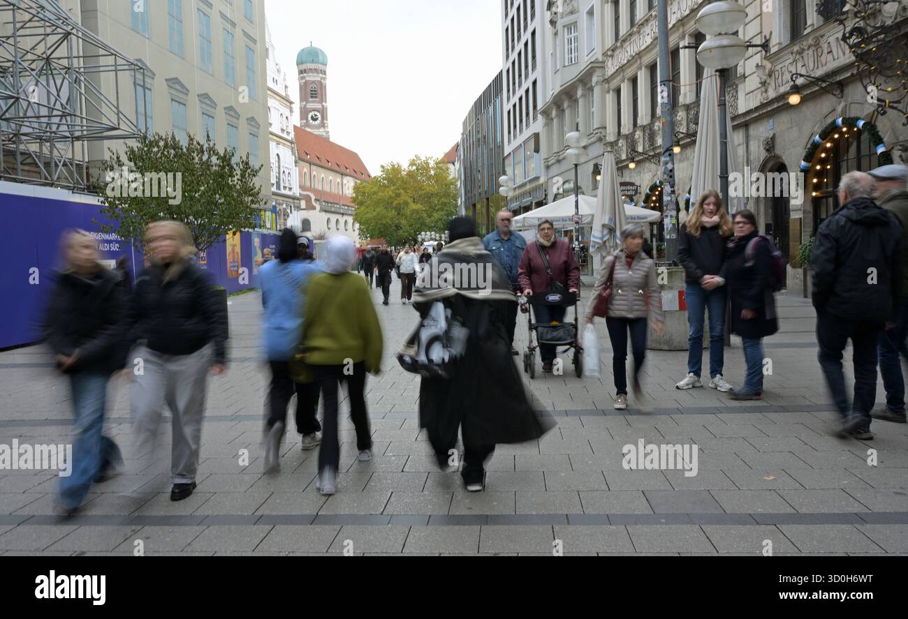 20 October 2025, Bavaria, Munich: Passers-by walk through Munich city ...