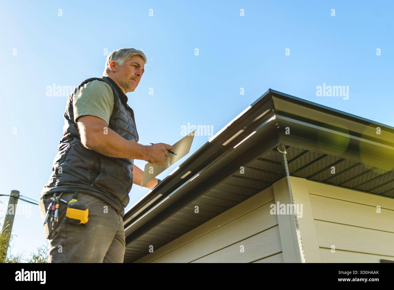 man standing on steps inspecting house roof Stock Photo - Alamy