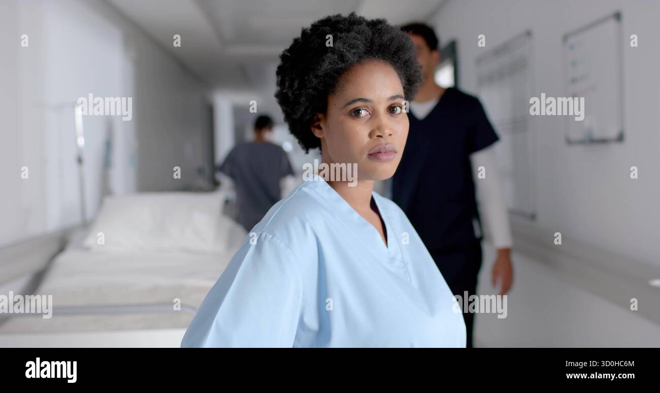 Standing nurse wearing light blue scrubs in hospital corridor, with ...