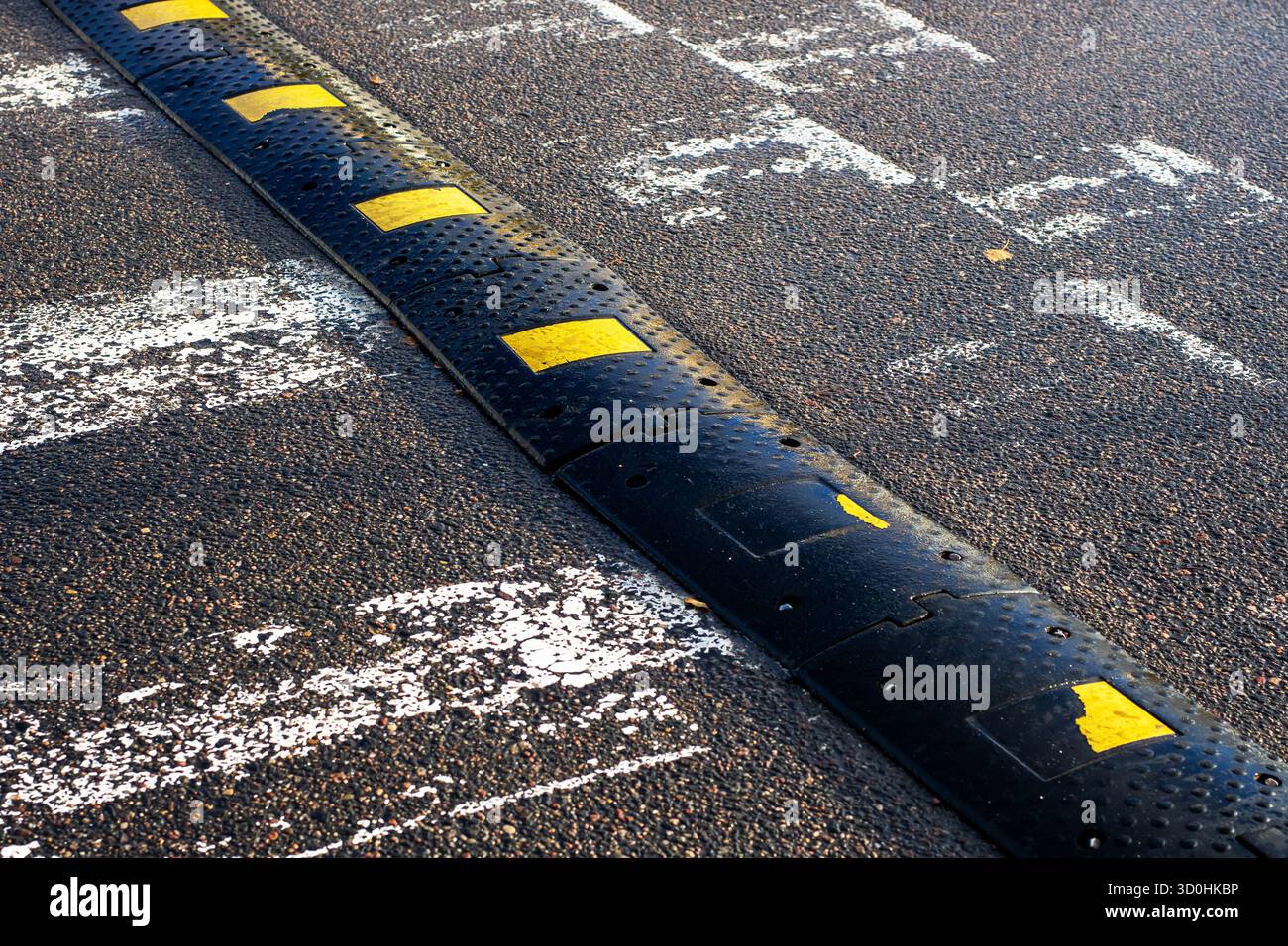 A close-up view of a traffic speed bump on an asphalt road, featuring ...