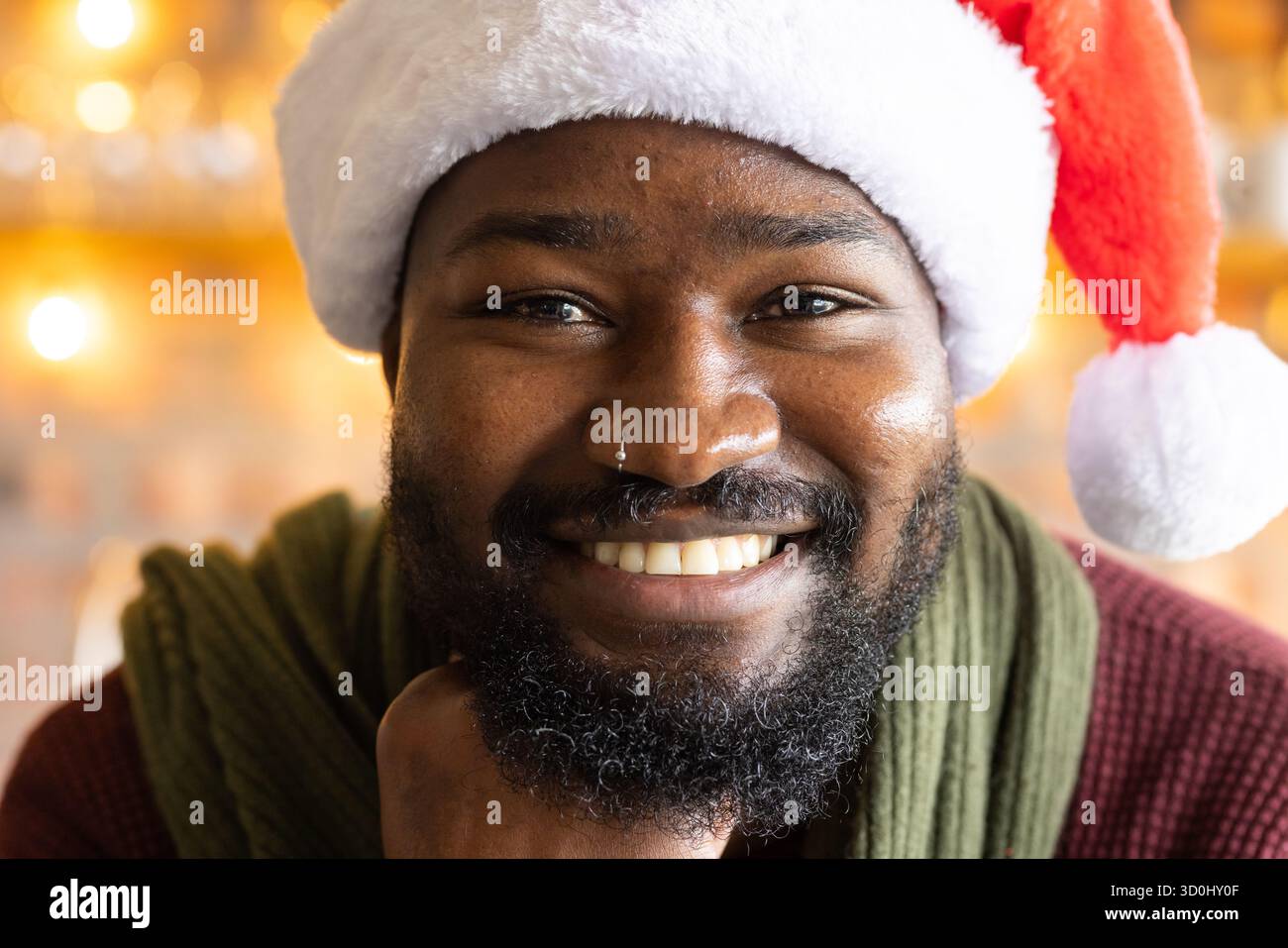 African American man smiling under string lights by brick wall donning ...
