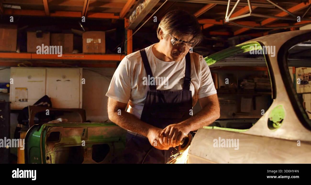 Grinding technician wearing coveralls at workshop with angle grinder ...