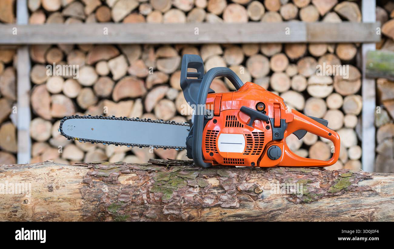 Closeup sharp petrol chainsaw on felled tree trunk before wall of ...