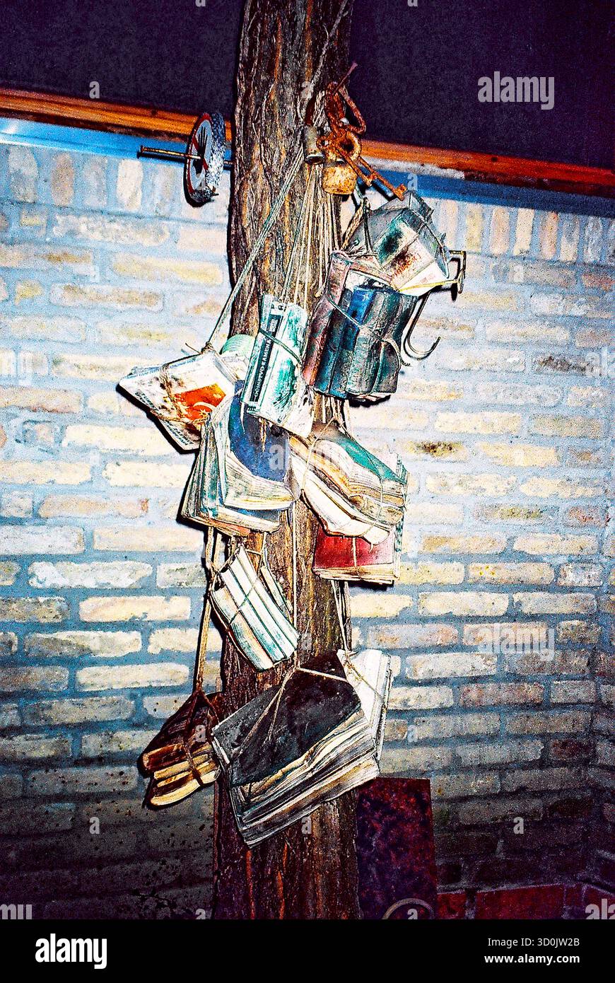 Bundles of tied books hanging from a tree trunk as a yard installation ...
