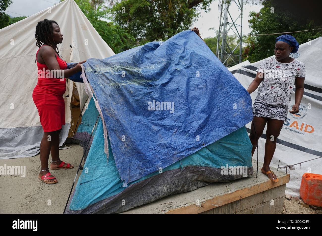 People place plastic tarps over their tents ahead of expected rain at a ...