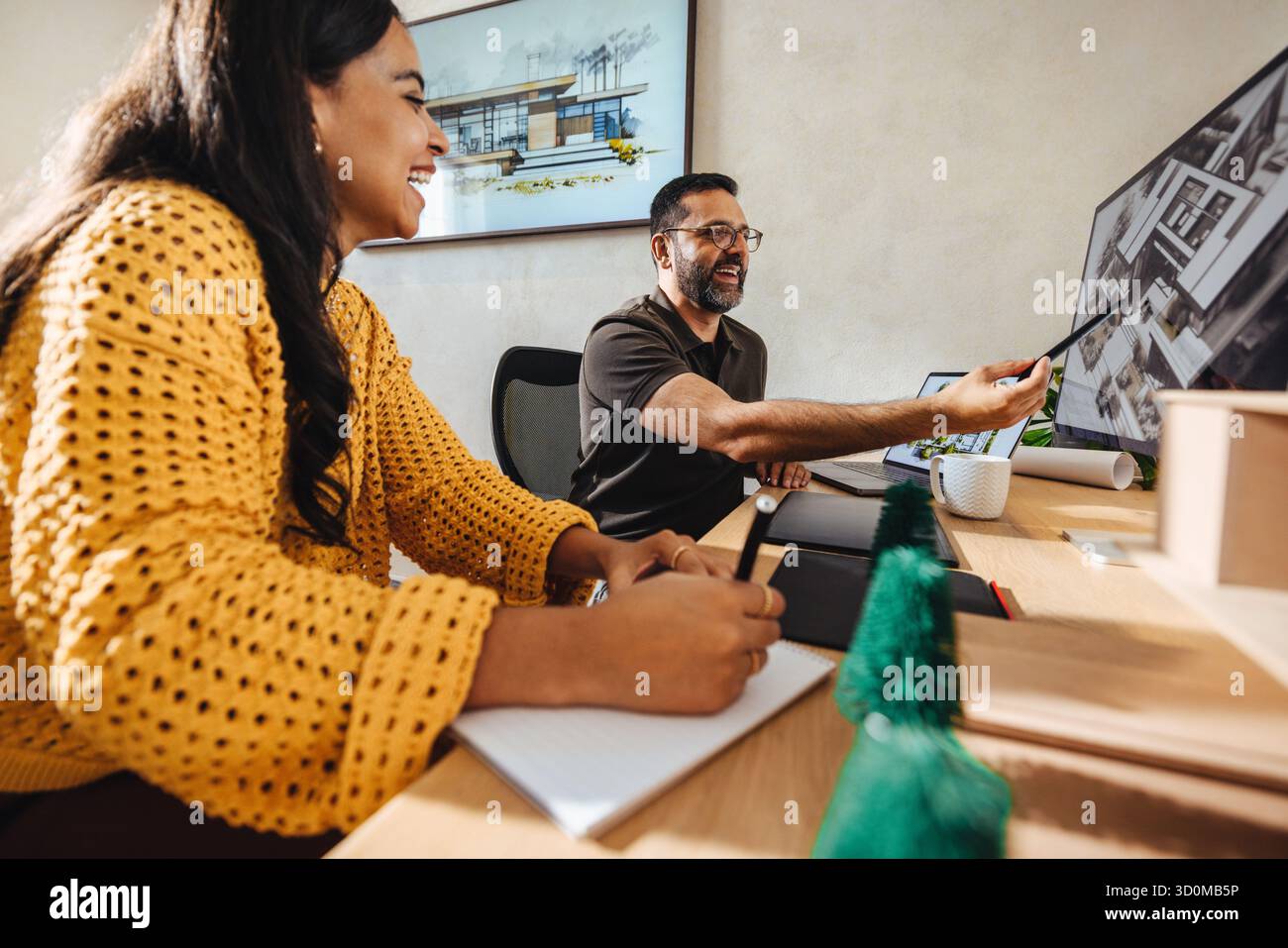 Two cheerful colleagues work together at their desk, analyzing ...
