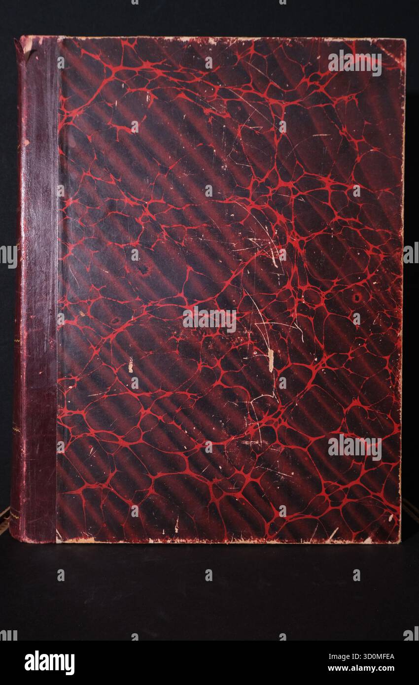 A closed antique book cover featuring a dark red and black marbled ...