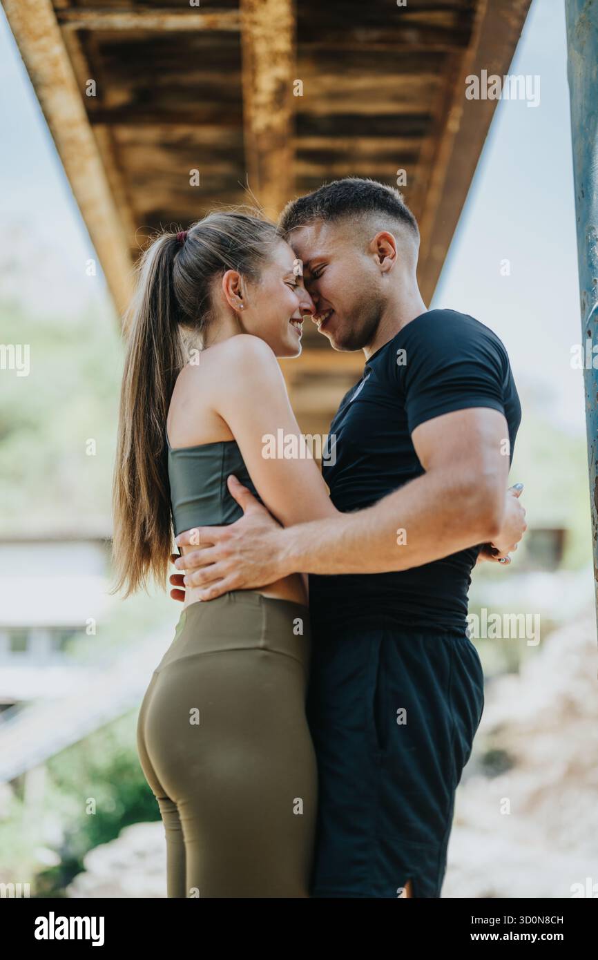 Couple embracing affectionately outdoors under a rustic bridge in a ...