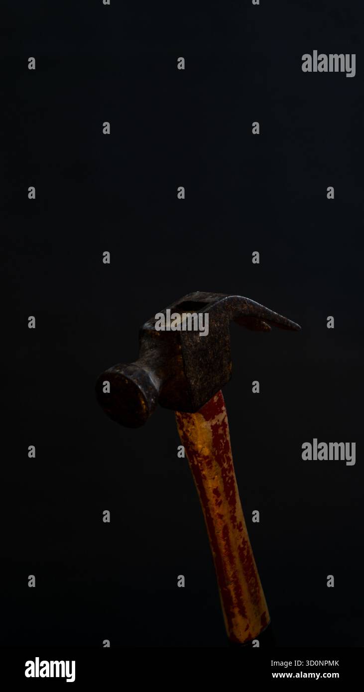 Isolated close-up of a hammer against a black background, vertical ...