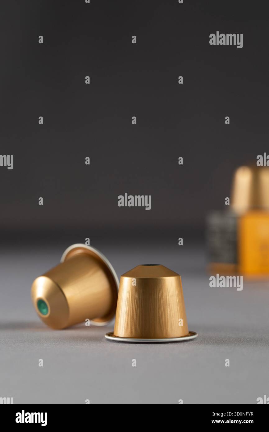 Gold coffee capsules arranged near a box on a gradient background ...