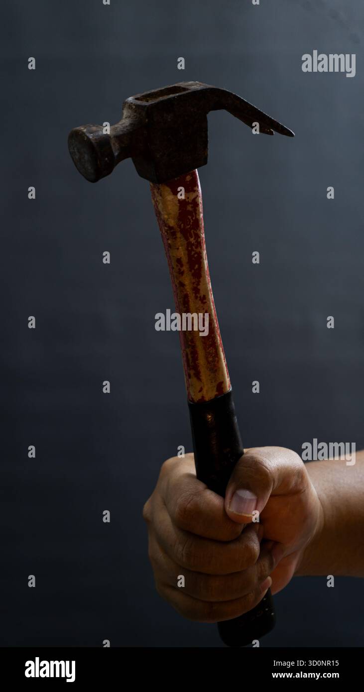 Vertical frame of a hammer held by a man’s hand gripping its black ...