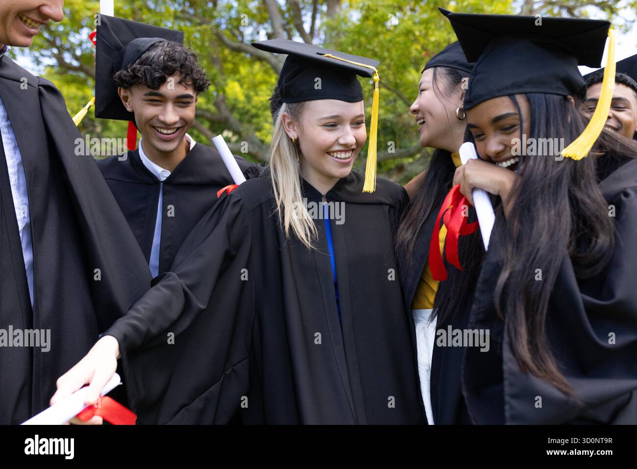 Graduating students in caps and gowns celebrating outdoors, smiling ...