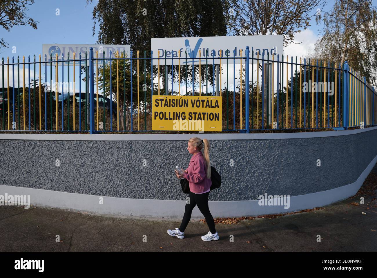 A woman walks past a sign for the polling station at Deaf Village in ...