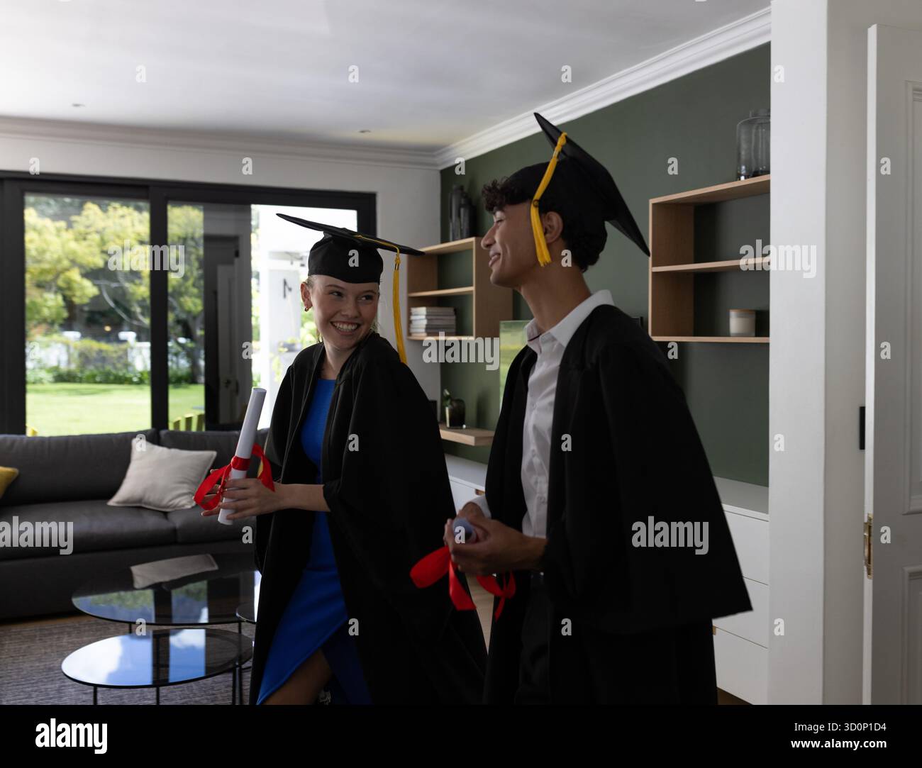 Celebrating graduation, teens in gowns smiling and holding diplomas at ...