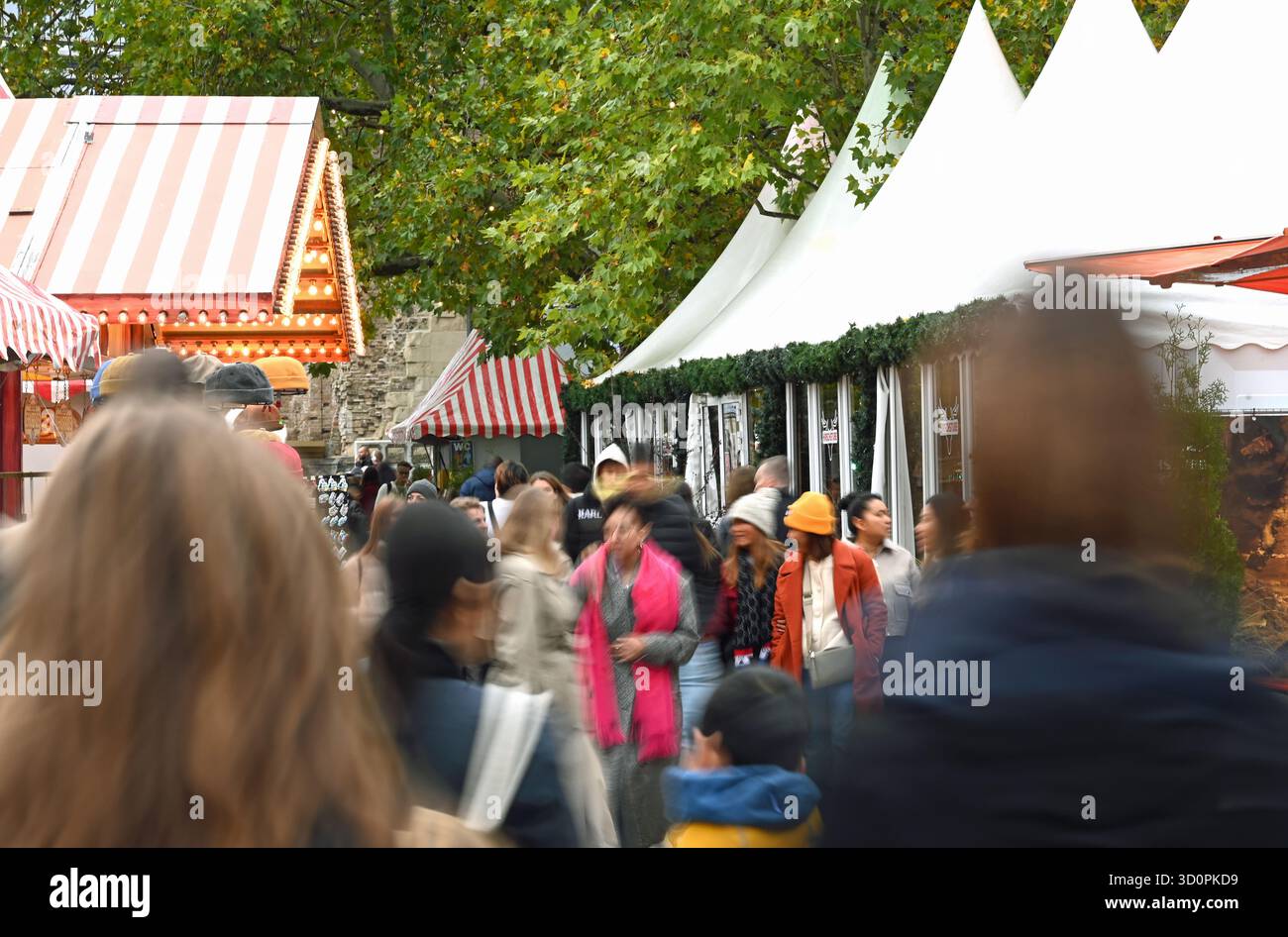 24 October 2025, Berlin: Passers-by walk through an alley of festively ...