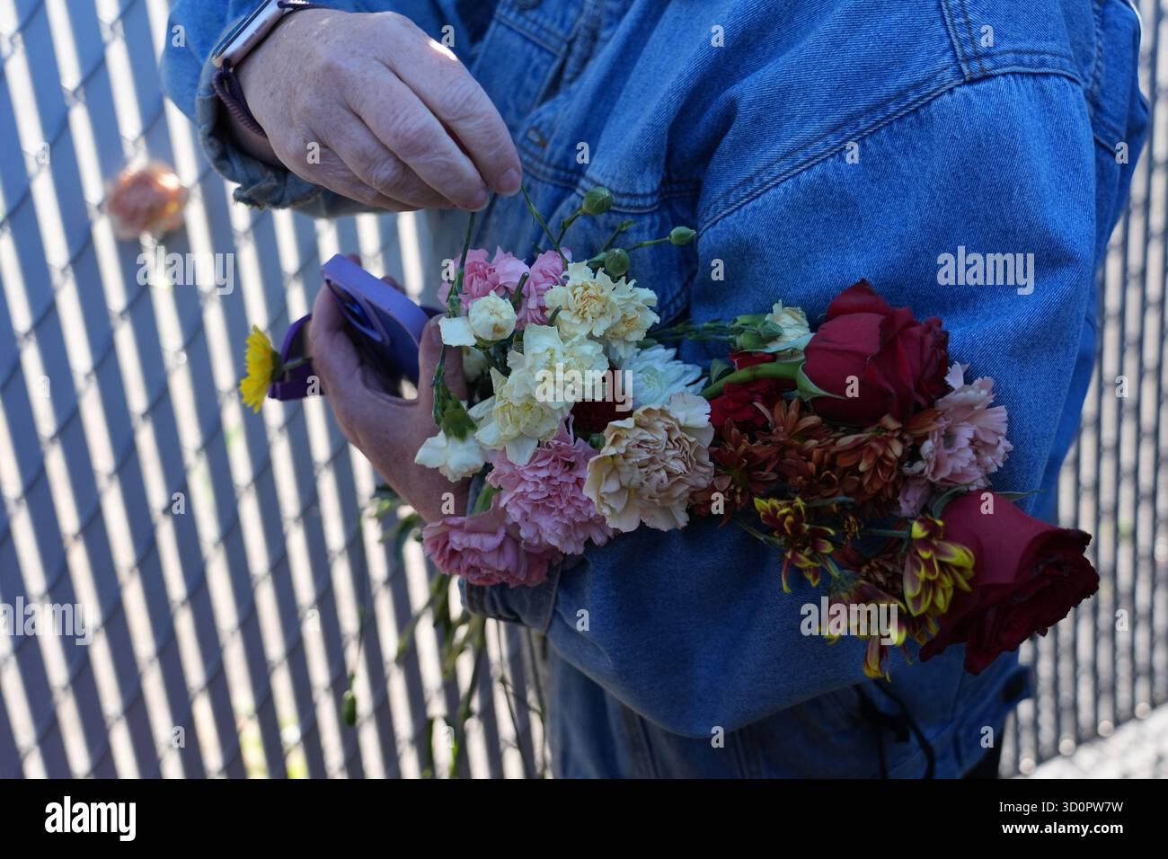 Protesters place flowers on the fence as they gather outside an ICE ...