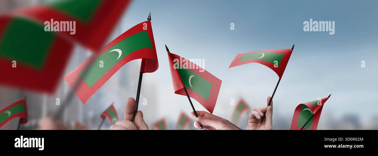 Maldives flags in their hands on a blurred urban background. The photo ...