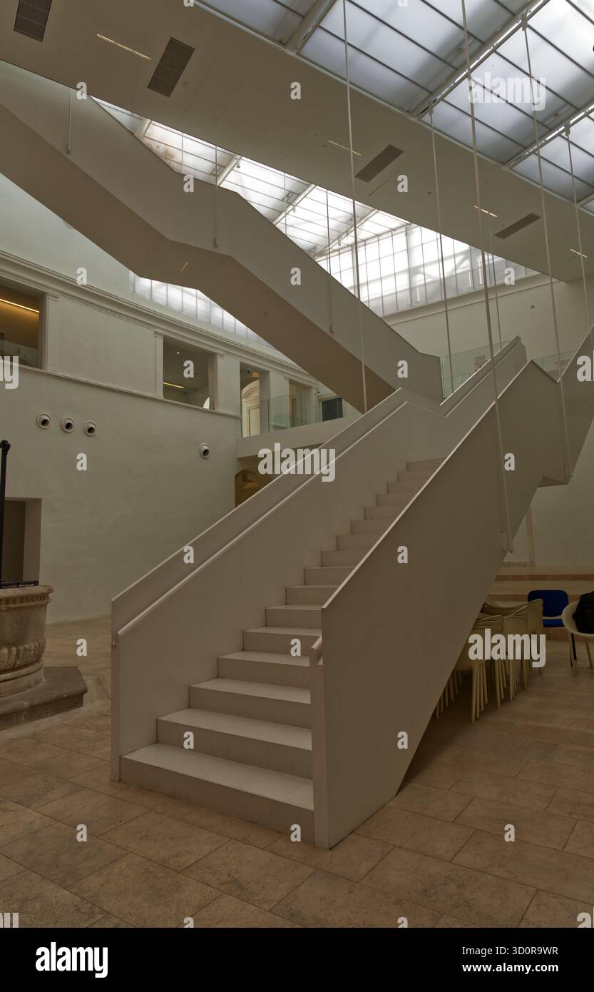 A modern interior featuring a split white staircase, translucent ...