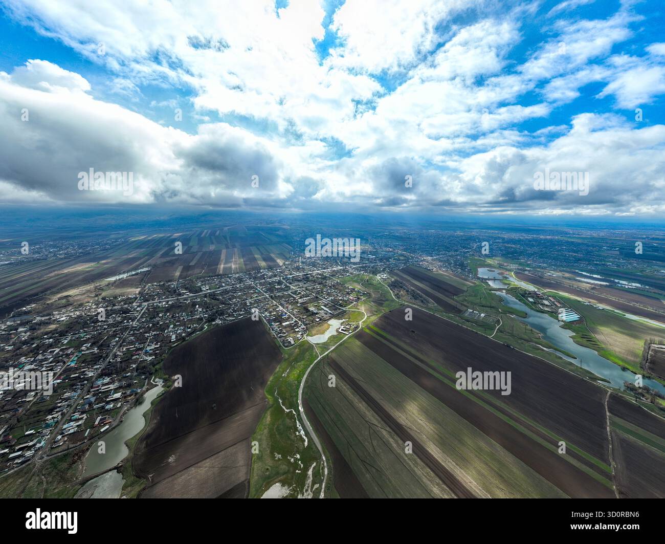 Expansive, high aerial perspective of villages and a distant urban area ...