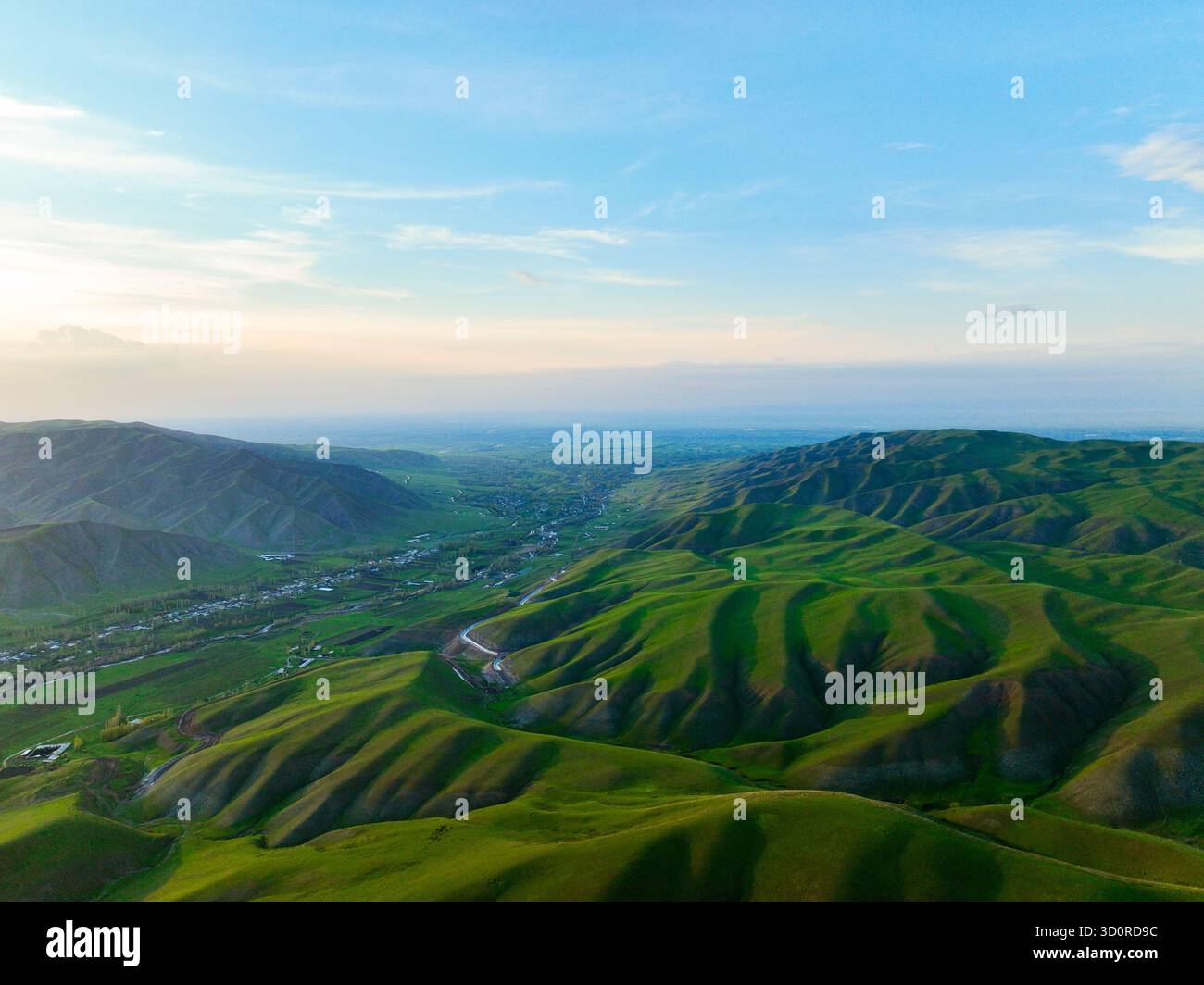 Expansive aerial view of lush, deep green, rolling hills and a winding ...
