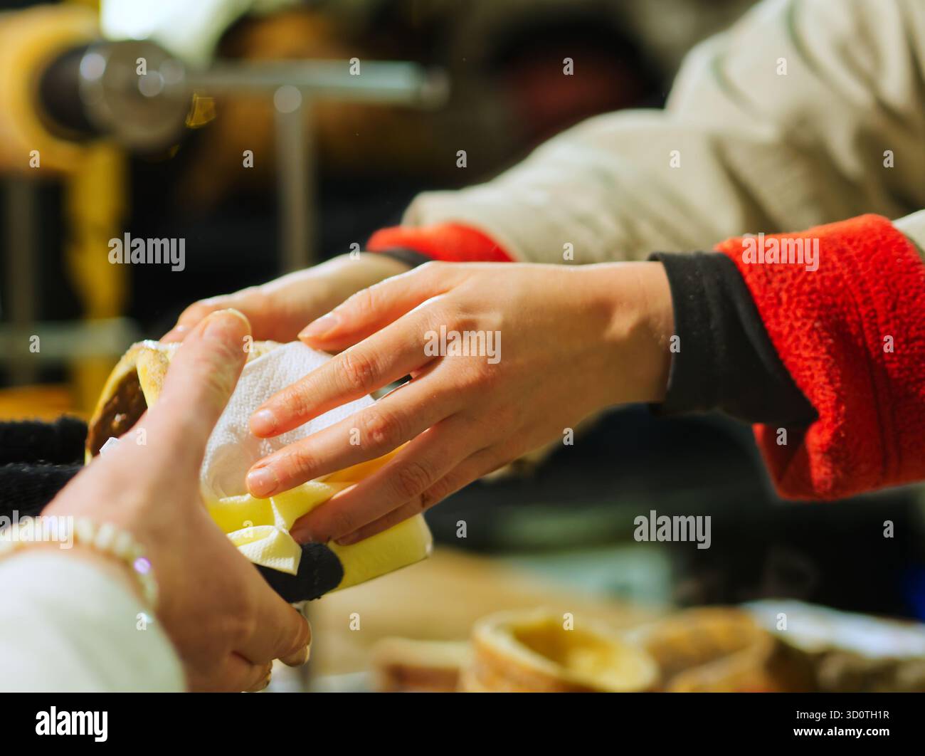 Chef's hands in red sleeves handling Trdelnik cinnamon roll in ...