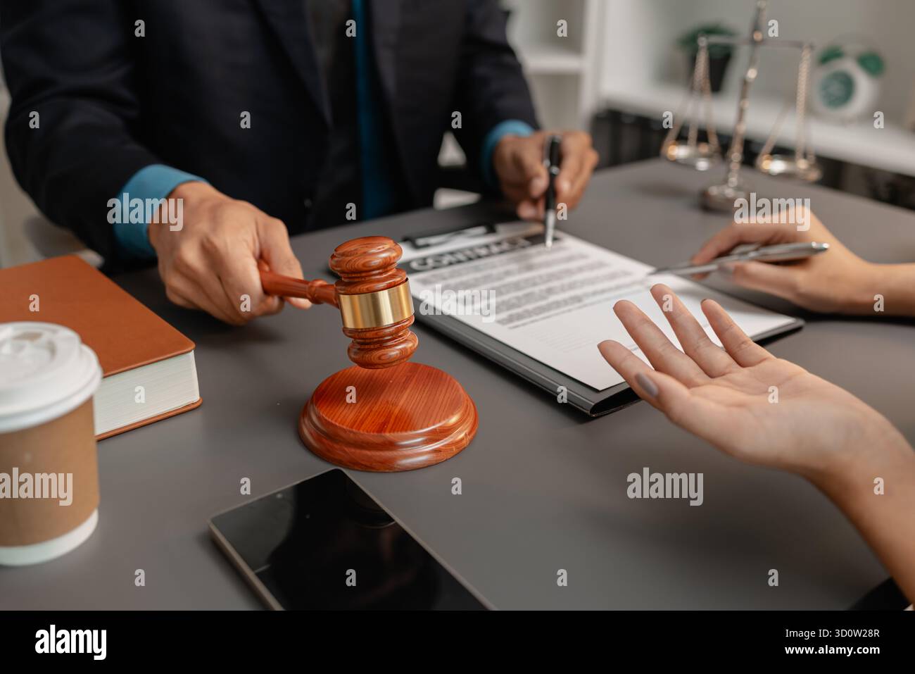 A male lawyer in a suit discusses contract details with a female client ...