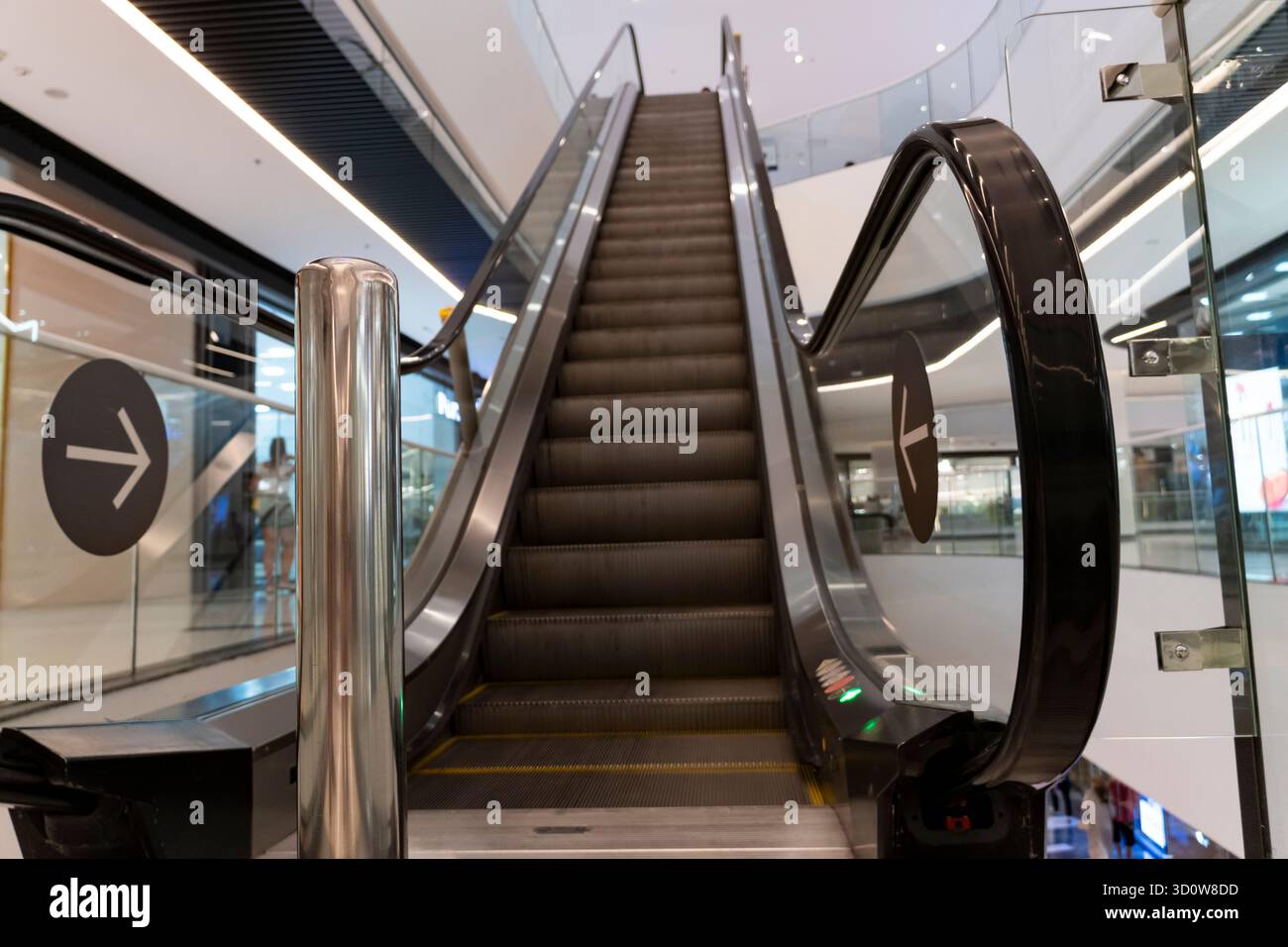 Contemporary indoor mall with glass railings, tiled floor, branded ...