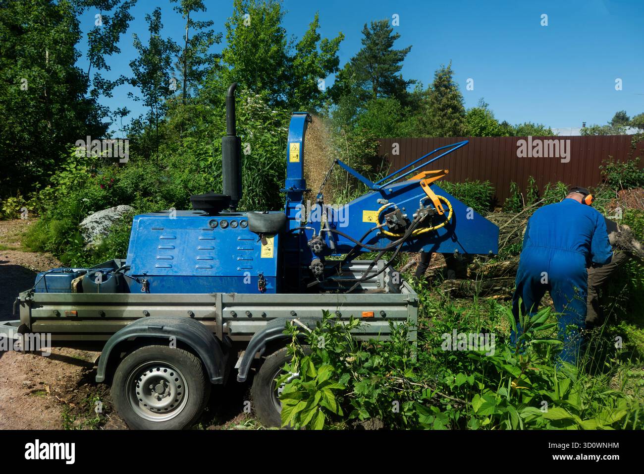 An operator loads tree branches into a wood chipper Stock Photo - Alamy