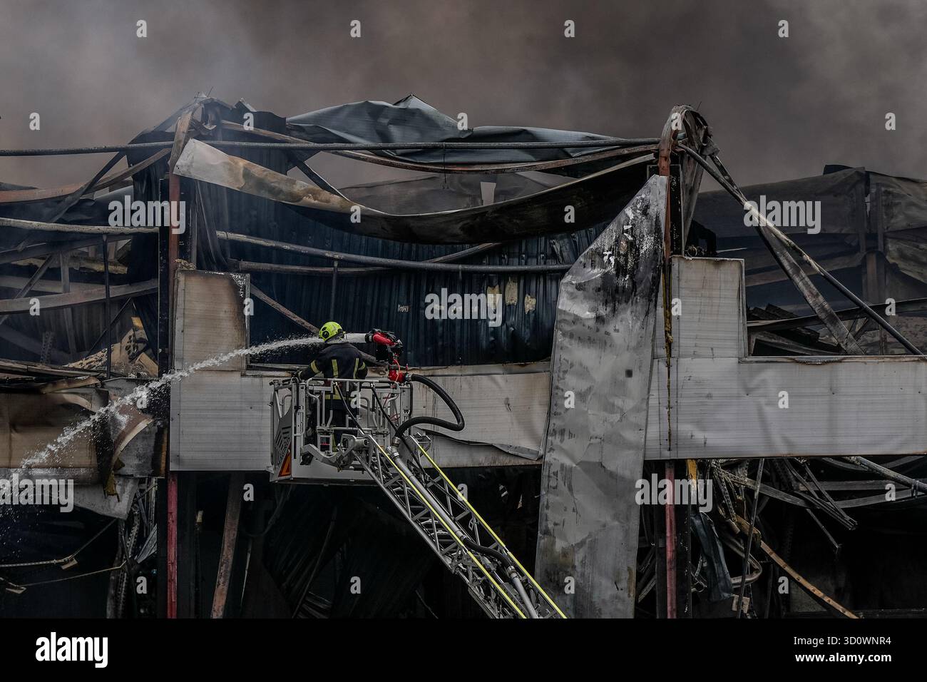 A firefighter works to extinguish a fire at a warehouse following a ...